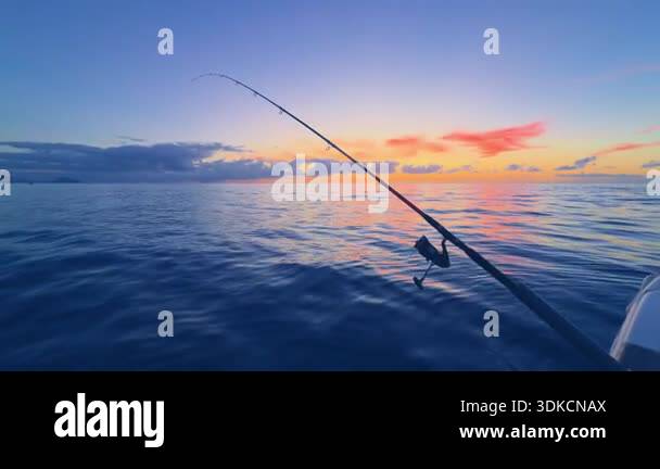 Offshore bottom fishing at sunset, rod on boat over calm sea, golden ...