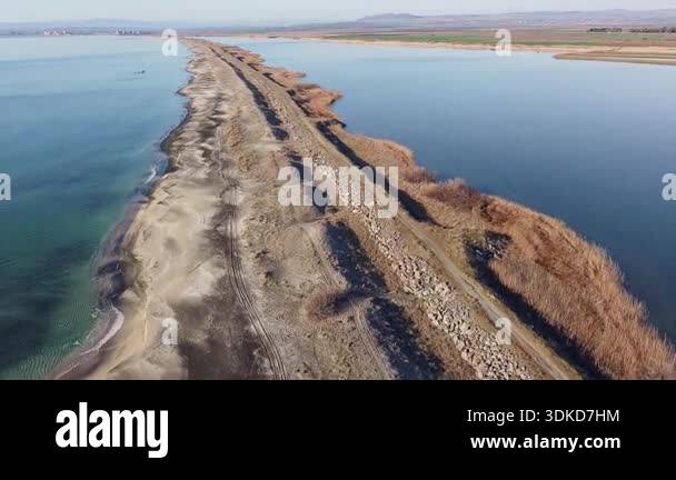 Birds eye view of narrow empty quiet beach with dry sand right and ...