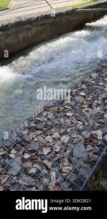 Rapid stream of water rushing through a concrete city canal reinforced ...
