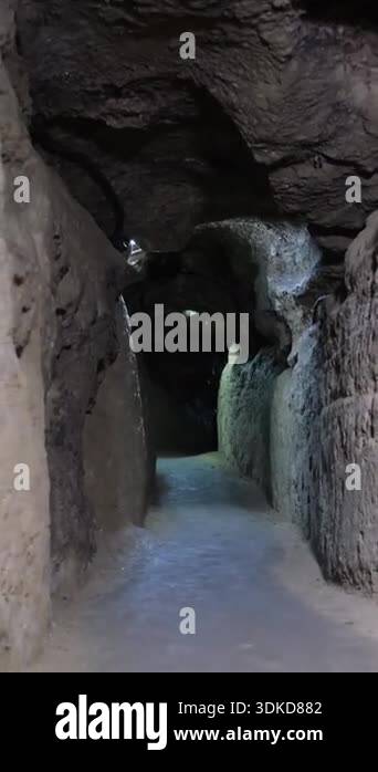 Forward walking movement through a dark and narrow ancient cave ...