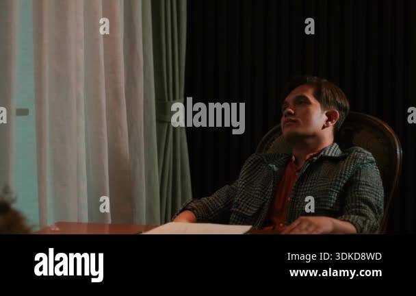 A thoughtful man leaning back in his chair, looking away in ...