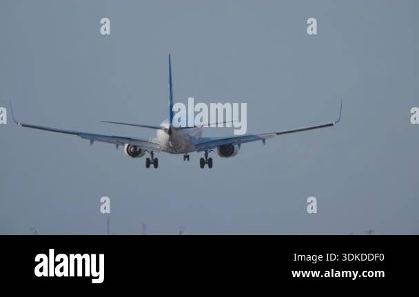 Video footage shows a passenger airplane landing on a runway. Rear view ...