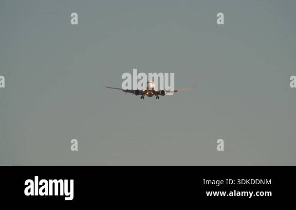 A commercial airliner approaches for landing against a clear sky. This ...