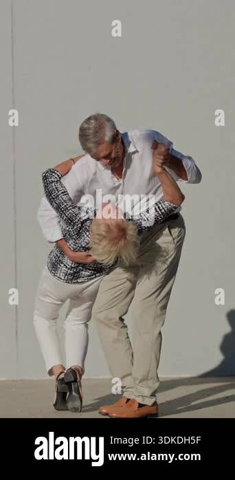 Happy retired couple enjoying a romantic tango dance together outdoors ...