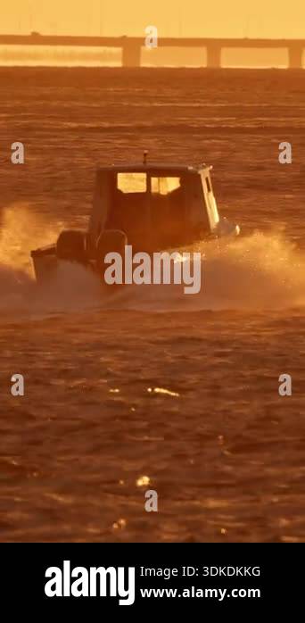Patrol boat quickly cruising on golden water surface at sunset Stock ...