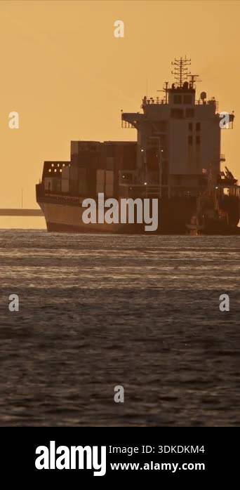 Container ship navigating calm waters during a golden sunset, with a ...