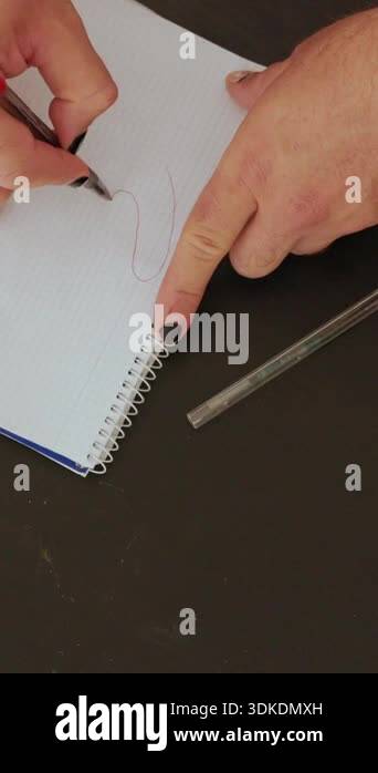 Man drawing the contour of his hand on a notepad using a pen Stock ...