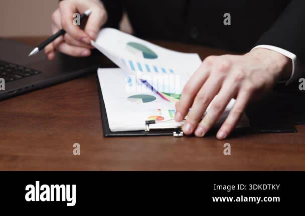 Person analyzing graphs on paper at desk Stock Video Footage - Alamy