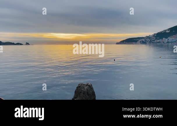 rock foreground overlooking coastal town sunrise with golden reflection ...