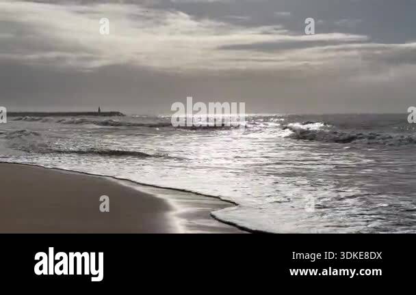 A sandy beach with gentle ocean waves lapping against the shore under ...