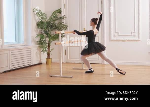 Young ballerina in tutu skirt stretching practicing ballet positions ...