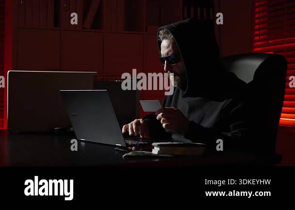 hacker typing code in dark office. Masked hacker hacking a computer in ...