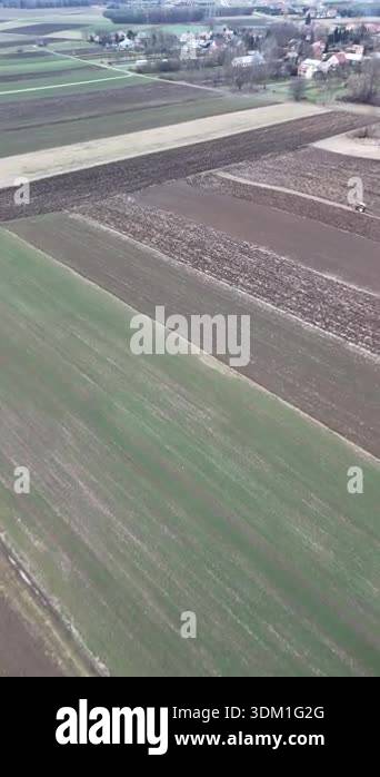 Sideways moving vertical drone shot above rural fields with village ...