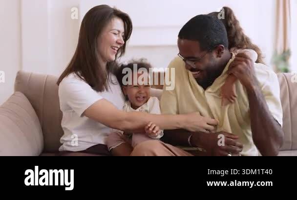 Happy interracial parents tickling their two laughing biracial children ...