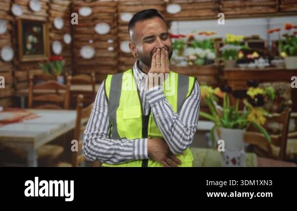 Man wearing reflective safety vest and striped shirt covers mouth ...