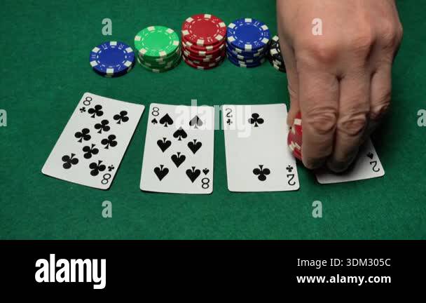 Hand positions a red poker chips on the table near playing cards ...