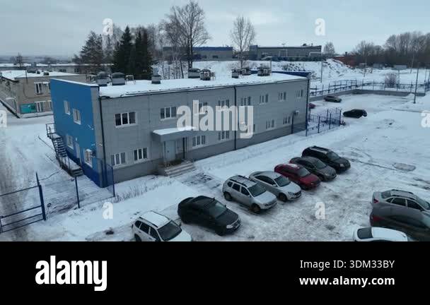 Cars stand on parking lot near administrative building of plant. Scene ...