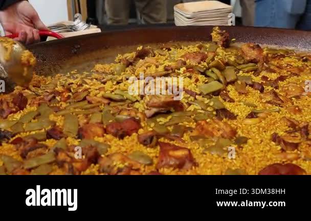 Close up of traditional paella being cooked in a large pan with rice ...