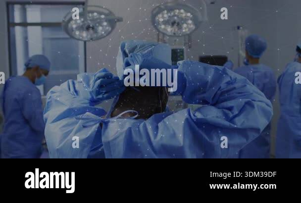 Lead surgeon tying cap before medical operation under lights while ...