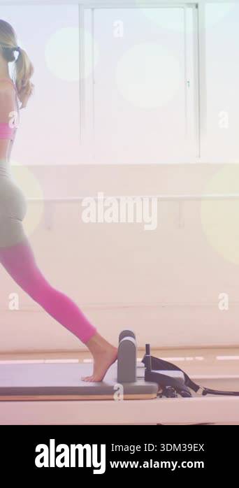 Exercising on Pilates reformer, woman stretching over bokeh light ...