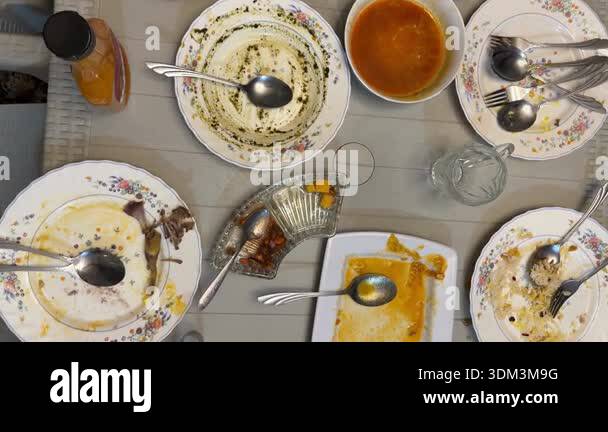 Top view tracking shot of dirty plates, leftover food, spoons and ...