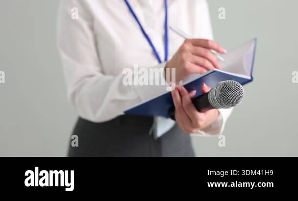Journalist with microphone taking notes on light background, closeup ...