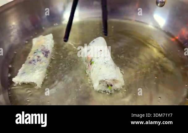 Vietnamese spring rolls frying in hot oil in pan, capturing authentic ...