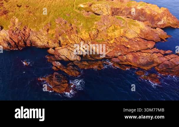 Rocks and ocean meet at the edge of a rugged coastline during sunset ...