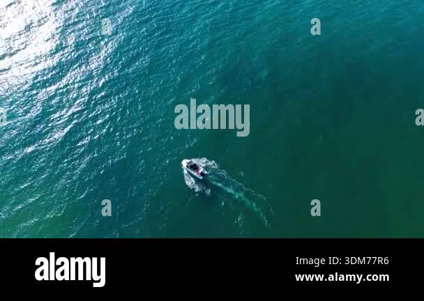 Boat travels across blue water during sunny day in open sea. A small ...
