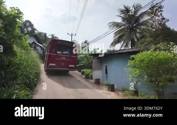 A passenger bus travels along a rural road through the jungle. High ...