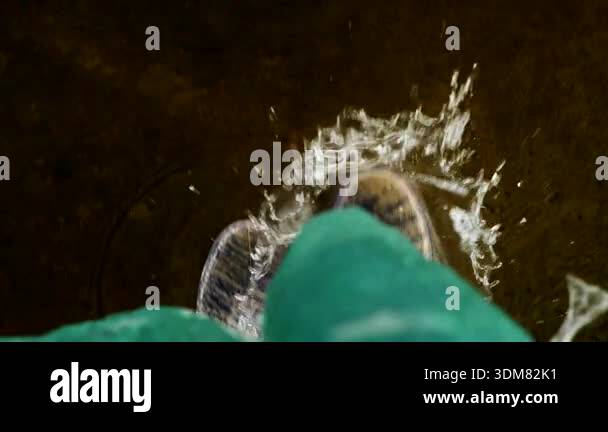 Blue patterned rain boot splashing vigorously into dark, muddy water ...