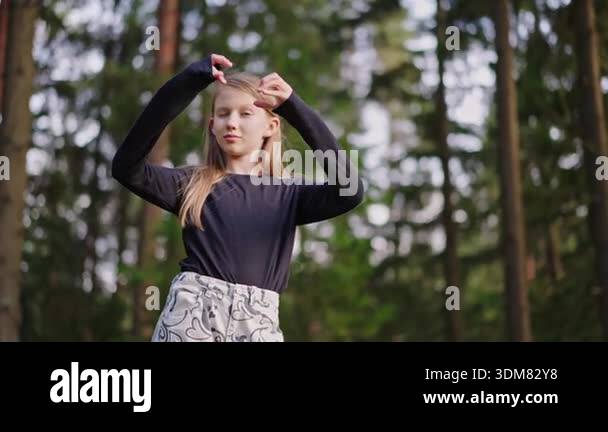 Teen girl gen Alpha stands outdoors in park, making a heart shape with ...