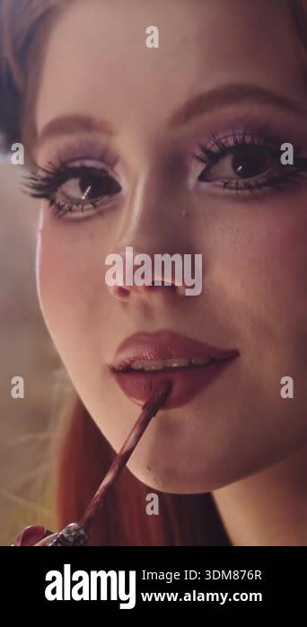 Cute young woman with catchy anime makeup applying matte lipstick on ...
