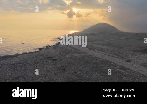 Aerial view of rugged volcanic coastline at sunset, golden light over ...