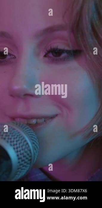 A cute young woman with light make up singing in the mic in the sound ...