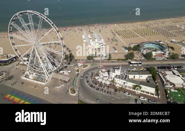 Aerial shot showing a large white ferris wheel on the seafront ...