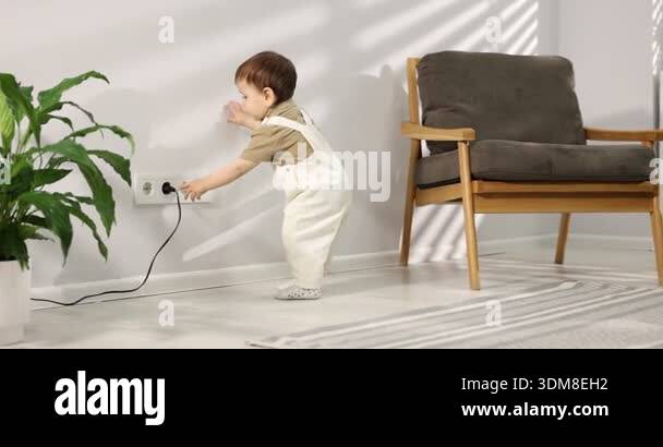 Child safety at home. Little boy taking plug out of power outlet ...