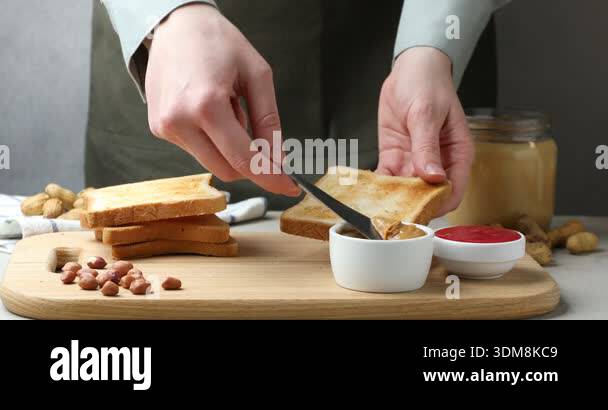Woman making sandwich with peanut butter at light table, closeup Stock ...