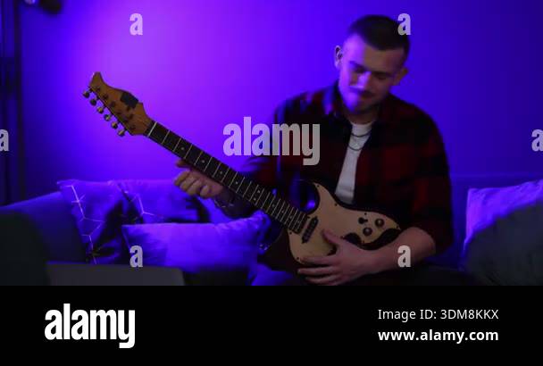 Man playing electric guitar and singing in color lights indoors. Camera ...