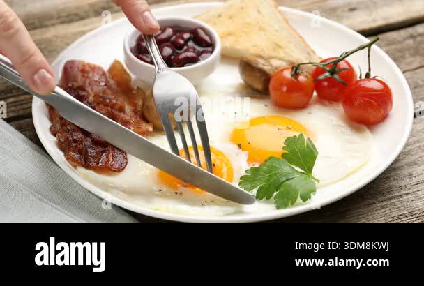 Traditional English breakfast. Woman eating delicious sunny side up ...