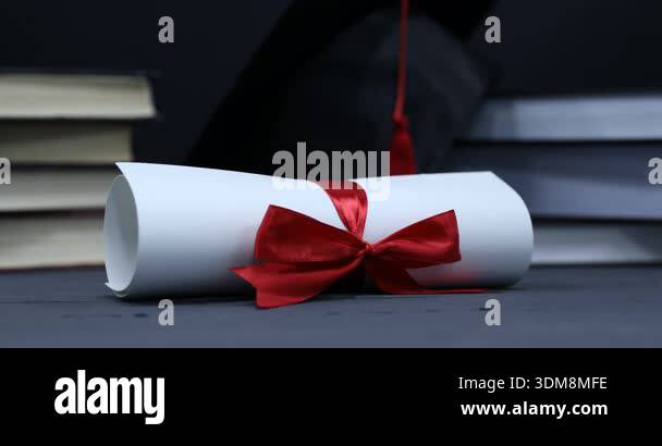 Woman taking diploma from grey wooden table with books and graduation ...