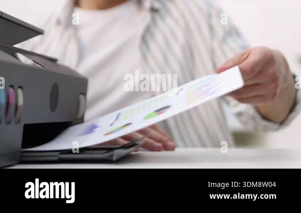 Man taking printed sheet of paper from printer at white desk indoors ...