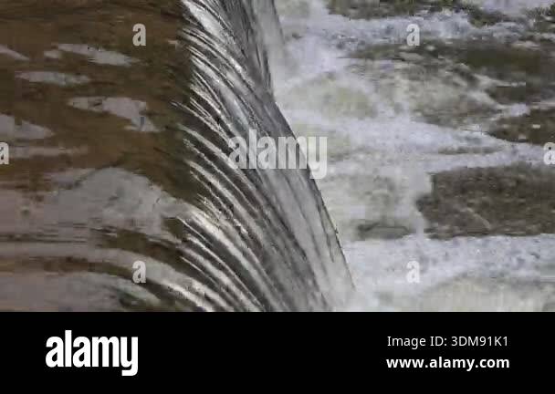 Close-up of water flowing over a concrete ledge creating a small ...