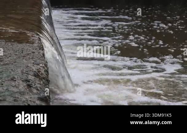 Close-up of water flowing over a concrete ledge creating a small ...