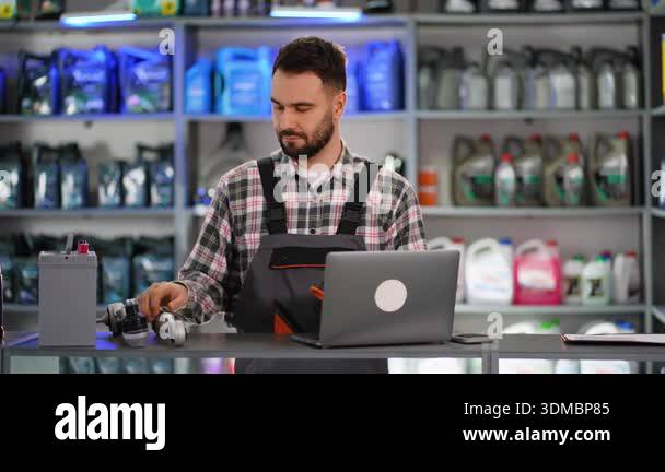 Professional male salesman in uniform working in a car parts store. The ...