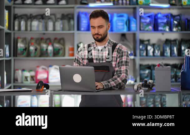 Male salesperson in an auto parts store using a laptop to check ...