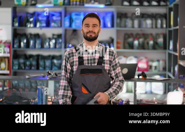 Friendly auto shop worker in uniform recommending quality engine oil ...