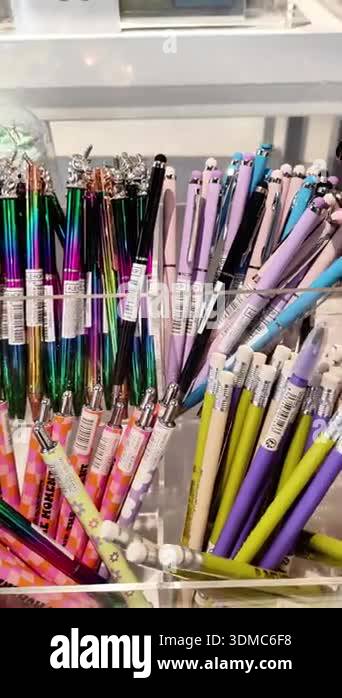Customers browse a collection of colorful pens at a store. The pens ...
