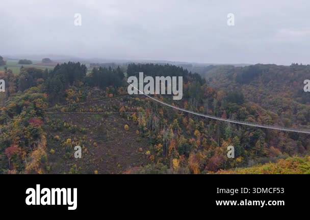 Panoramic view curved bridge across valley, overcast skies and sweeping ...