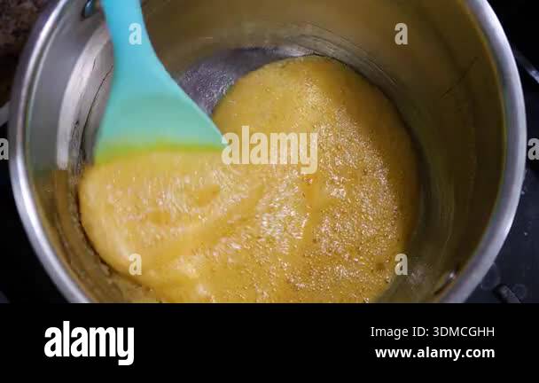 Caramel preparation in a pot. Stirring golden liquid sugar. Sweet ...